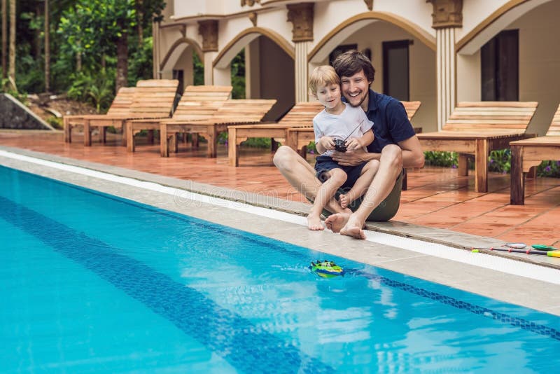 Father and Son Playing with a Remote Controlled Boat in the Pool Stock ...