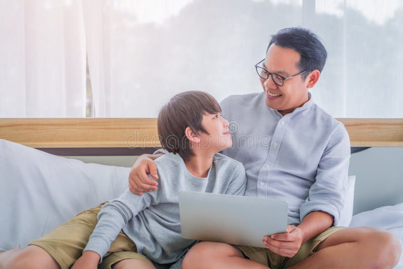 Father and Son Using Laptop Computer on the Bed Together for Technology ...