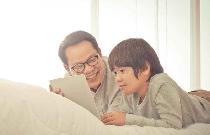 Father and Son Using Laptop Computer on the Bed Together for Technology ...