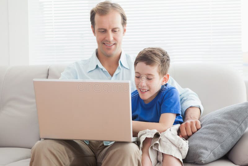 Father and Son Using Laptop on the Couch Stock Photo - Image of ...