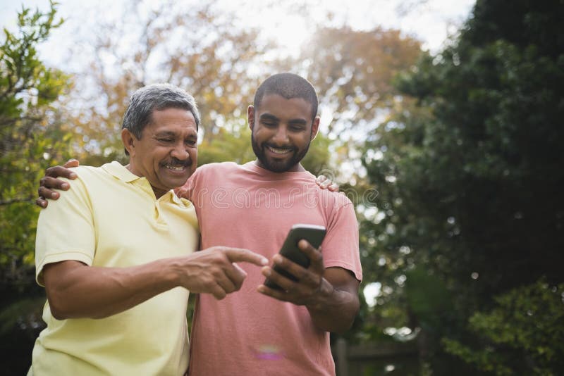 Father and Son Using Mobile Phone at Park Stock Image - Image of length ...