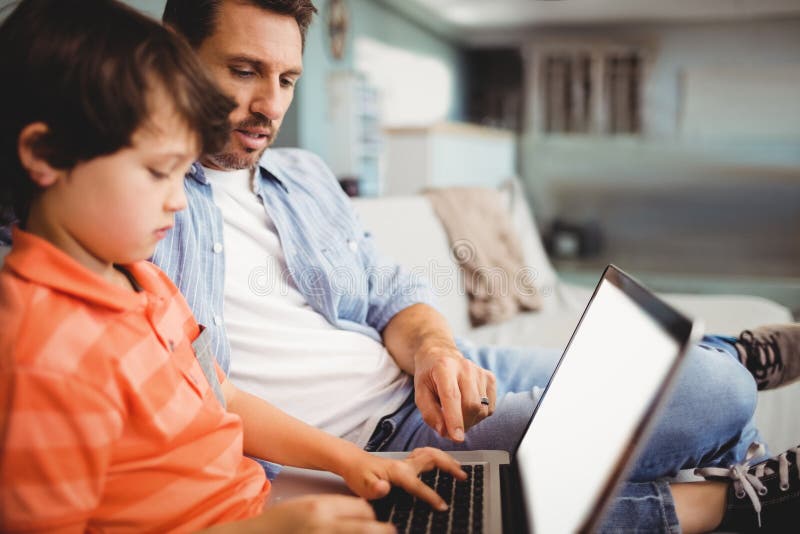 Father and Son Working on Laptop while Sitting on Sofa Stock Photo ...