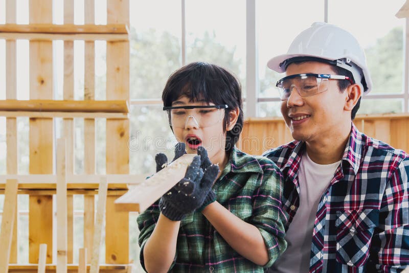 Father and Son are Working on Wood in the Workshop. Little Boy is ...