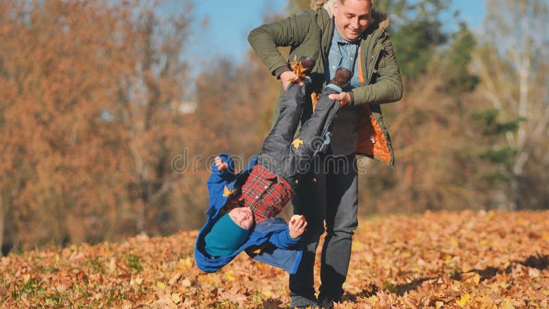 A Father Spins His Son by His Feet in the Park in the Fall. Stock Image ... A Father Spins His Son by His Feet in the Park in the Fall. Stock Image ...