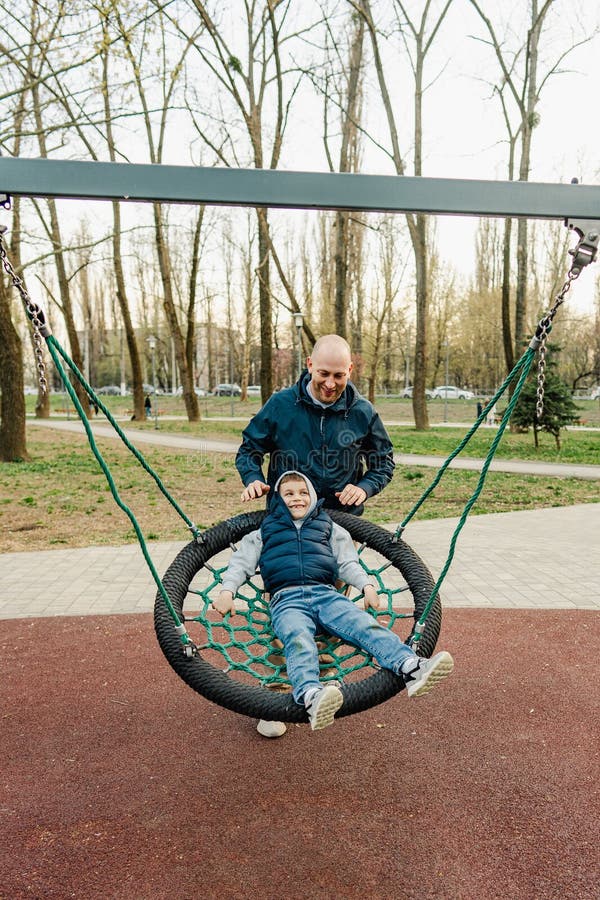 Father Swinging His Son on a Swing on Playground in Park Stock Image ...