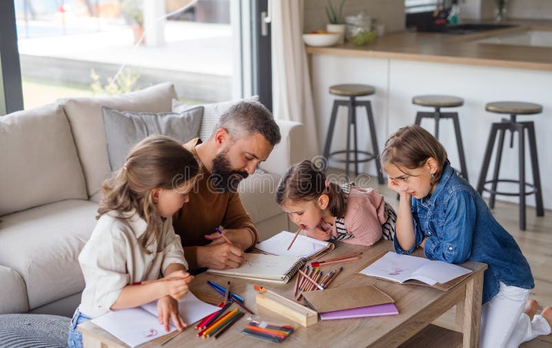 Father With Three Daughters Indoors At Home Drawing Pictures Stock