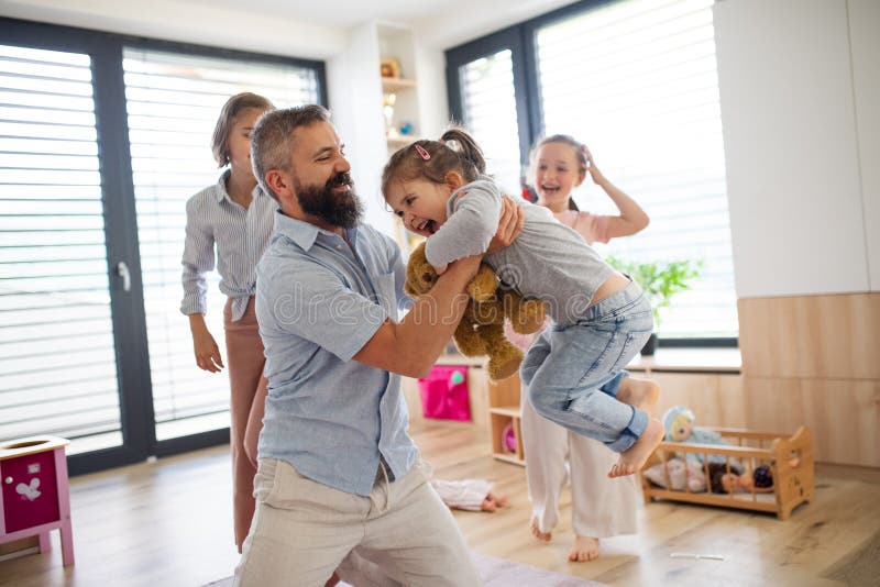 Father With Three Daughters Indoors At Home Playing On Floor Stock