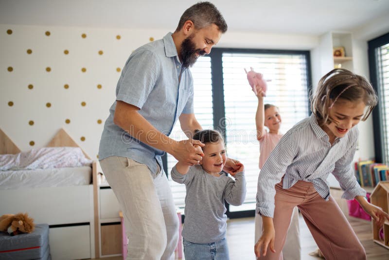 Father With Three Daughters Indoors At Home Playing And Holding Hands