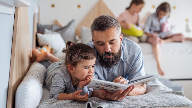 Father with Three Daughters Indoors at Home, Reading a Book. Stock ...