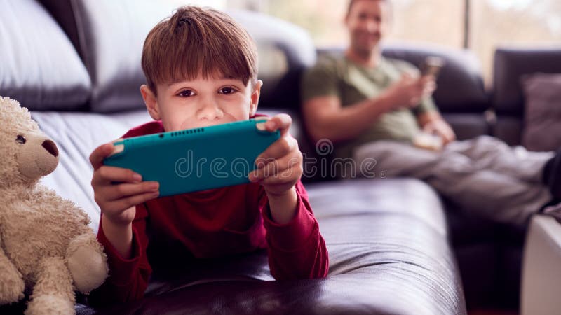 Father Uses Mobile Phone As Son Plays Computer Game on Portable Gaming ...
