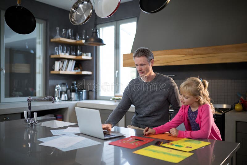Father Using a Laptop while Daughter is Coloring Stock Photo - Image of ...