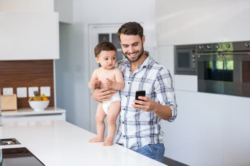 Father Using Mobile Phone while Holding Baby Boy Stock Photo - Image of ...