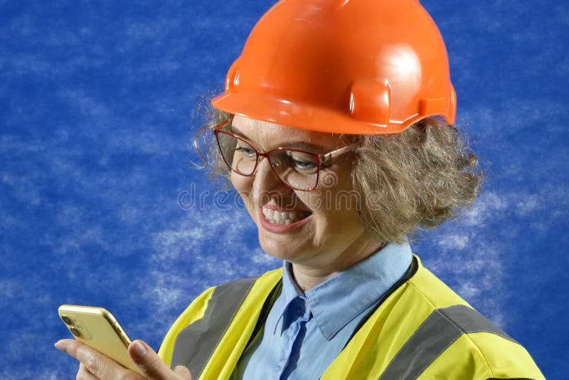 Feamle Engineer in the Construction Helmet with Mobile Phone on Blue ...