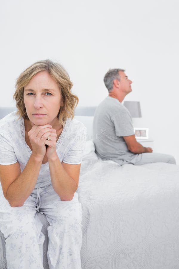Fed Up Couple Sitting On Different Sides Of Bed Having A Dispute Stock