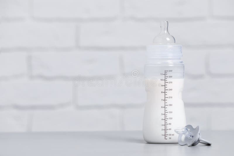 Feeding Bottle with Infant Formula and Pacifier on Light Grey Table ...