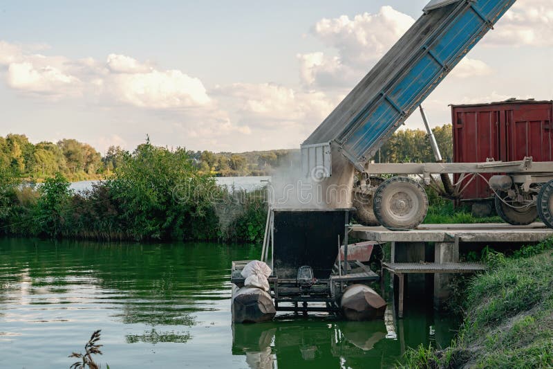 Feeding Fish in a Fish Farm. Loading Fish Feed into the Boat from the ...
