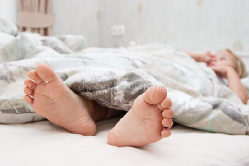 Feet Under a Light Blanket on the Bed. Concept of Healthy Stock Image ...