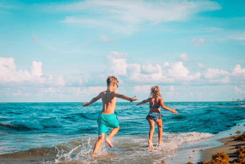 Feliz Garoto E Garota Jogam Na Praia Foto De Stock Imagem De Povos