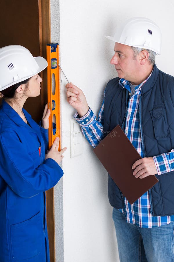 Female Apprentice Checking Level Door Frame while Architect Supervises ...