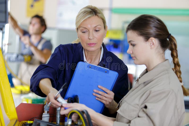 Female Apprentice and Instructor Using Machine in Factory Stock Photo ...