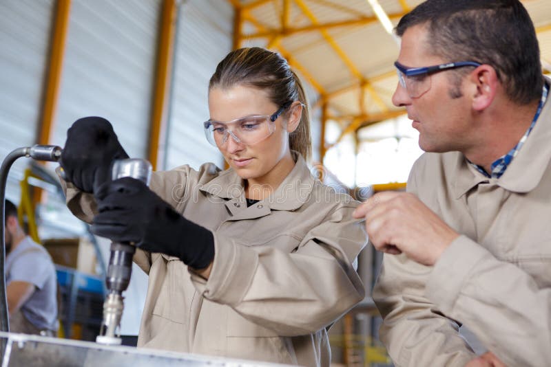 Female Apprentice Using Drill Under Supervision Stock Image - Image of ...