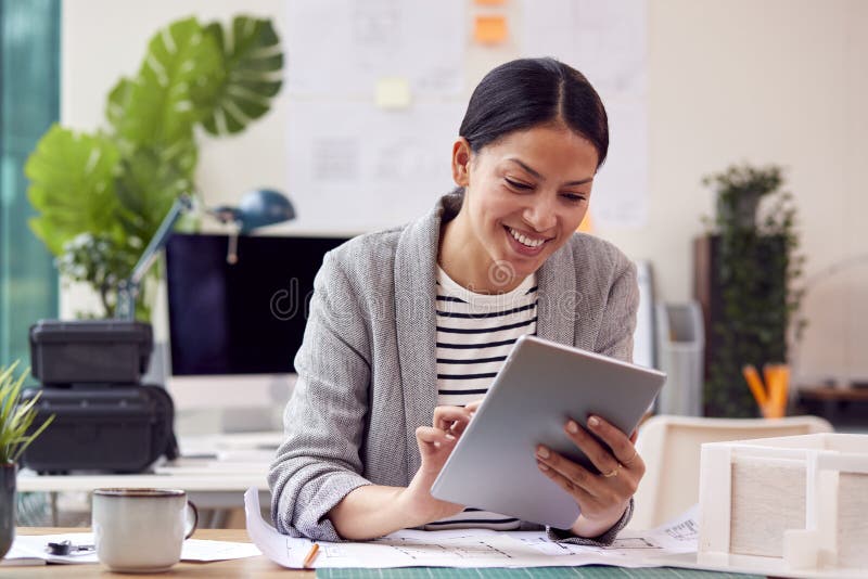Female Architect in Office Sitting at Desk Working on Digital Tablet ...