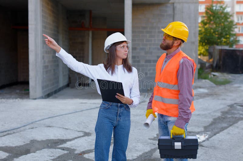 Female Architect Pointing at Something while Discussing with ...