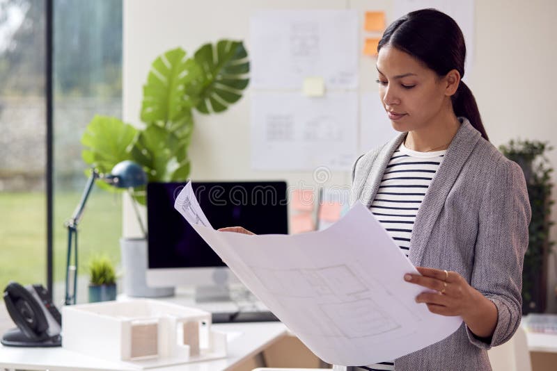 Female Architect Standing in Office Looking at Building Plans Stock ...