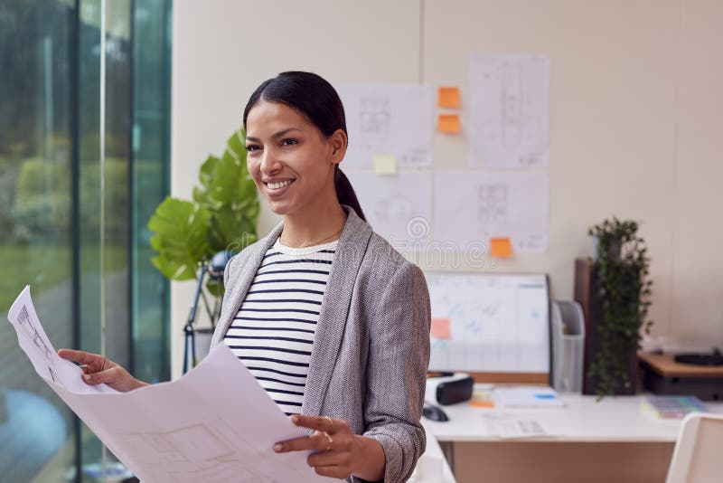 Female Architect Standing in Office Looking at Building Plans Stock ...