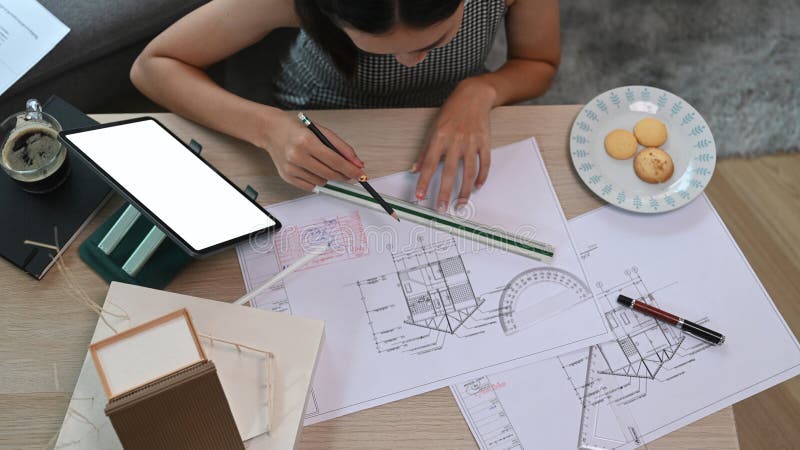 Female Architect Working at Home with Tablet and Blueprints. Stock ...