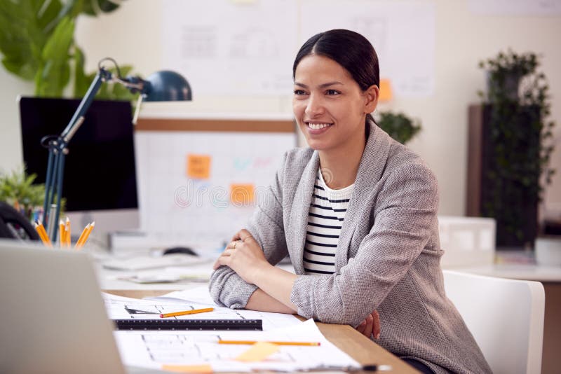 Female Architect Working in Office at Desk Working on Plans for New ...