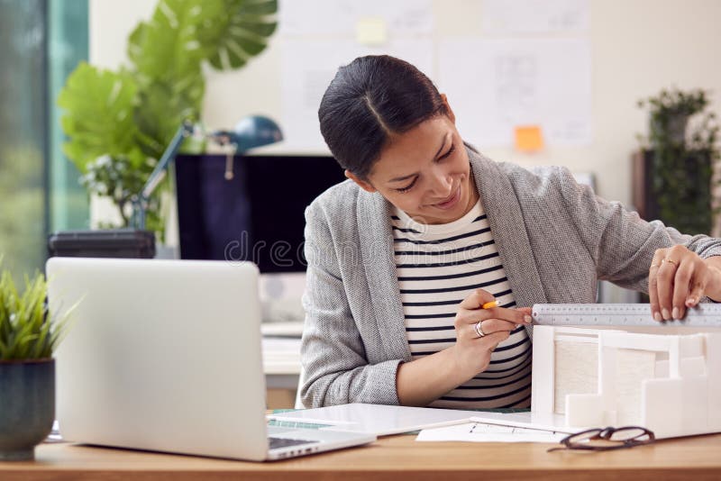 Female Architect Working in Office Sitting at Desk Studying Model of ...
