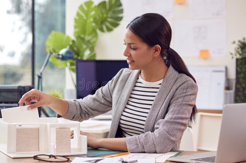 Female Architect Working in Office Sitting at Desk Studying Model of ...