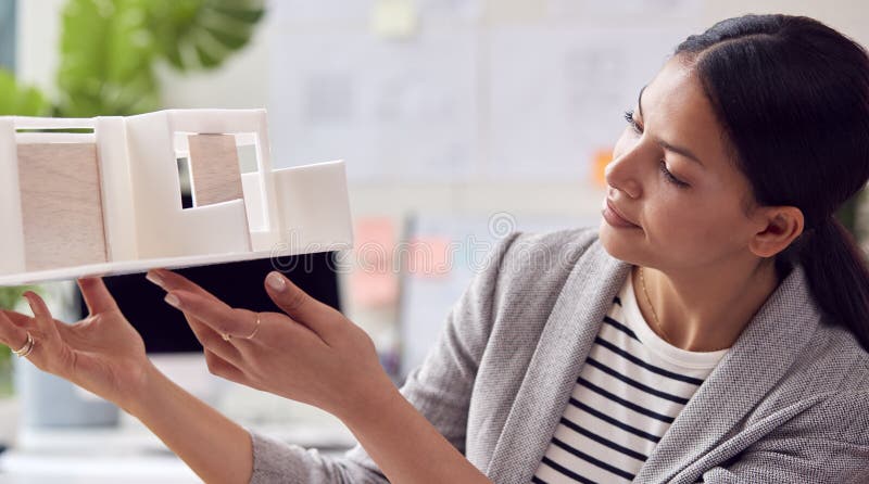 Female Architect Working in Office Studying Model of New Building Stock ...