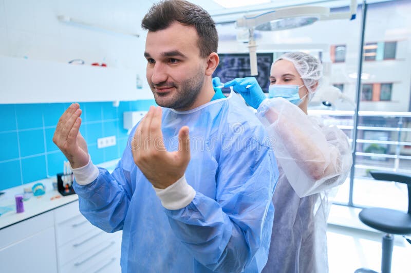Female Assistant Puts on a Disposable Sterile Uniform for Doctor Stock ...