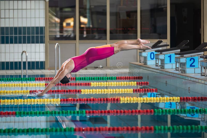 Female Athlete Preparing for a Dive Start and Jumping into the Pool ...
