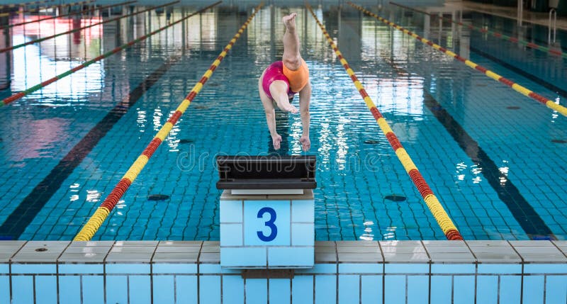 Female Athlete Preparing for a Dive Start and Jumping into the Pool ...