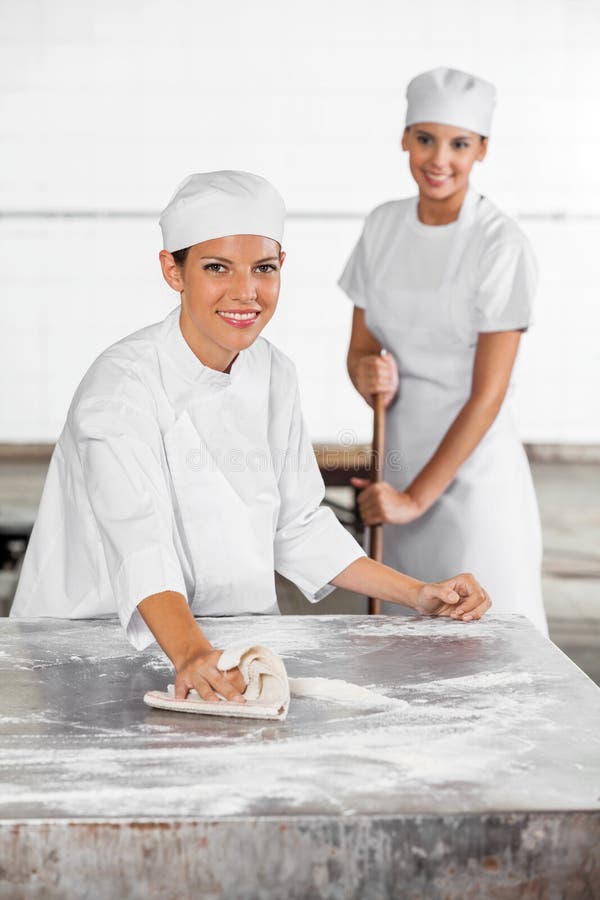 Female Baker Cleaning Table while Colleague Using Stock Image - Image ...