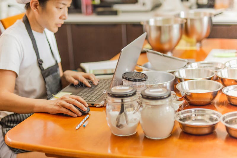 Female Baker Working on Laptop with Bakery Ingredient on Table. Stock ...