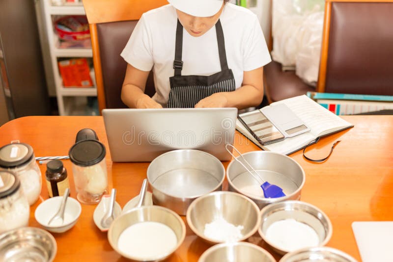 Female Baker Working on Laptop with Bakery Ingredient on Table. Stock ...