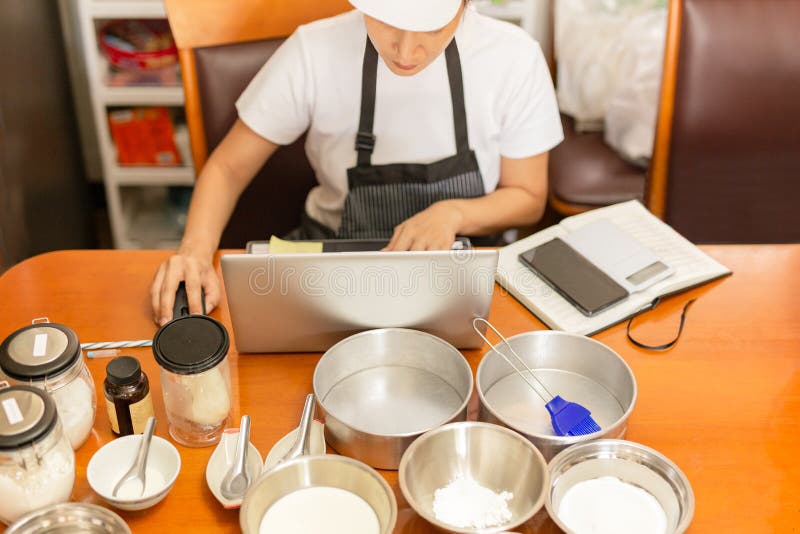 Female Baker Working on Laptop with Bakery Ingredient on Table. Stock ...