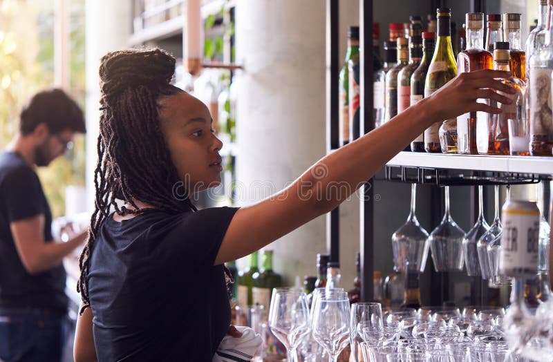 Female Bartender Arranging Bottles of Alcohol Behind Bar Stock Image ...
