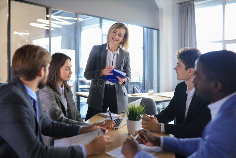 Female Boss Addressing Meeting Around Boardroom Table. Stock Image ...