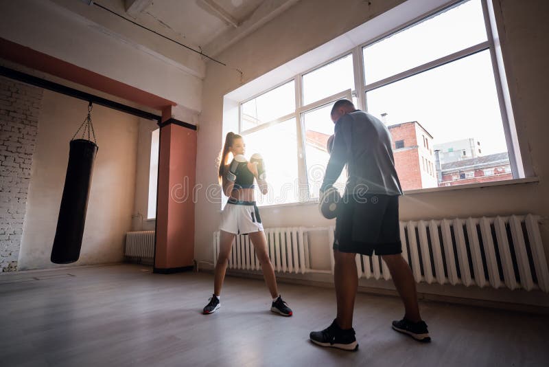 Female Boxer Practicing Hits with Her Personal Trainer in a Boxing ...