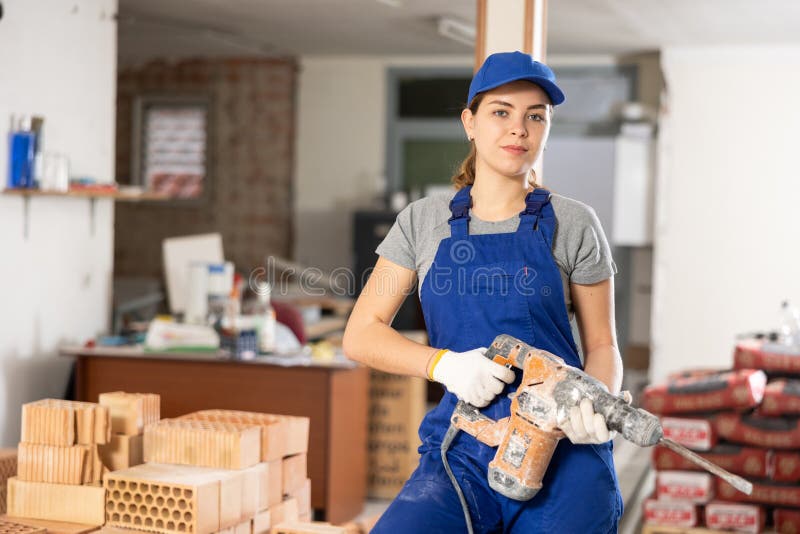 Female Builder in Blue Overalls Standing at Construction Site with ...