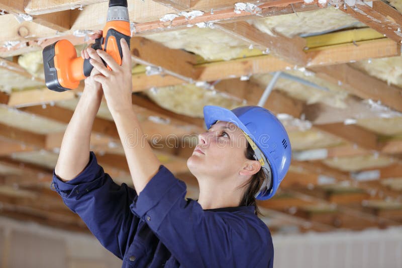 Female Builder Using Cordless Drill on Ceiling Joists Stock Photo ...