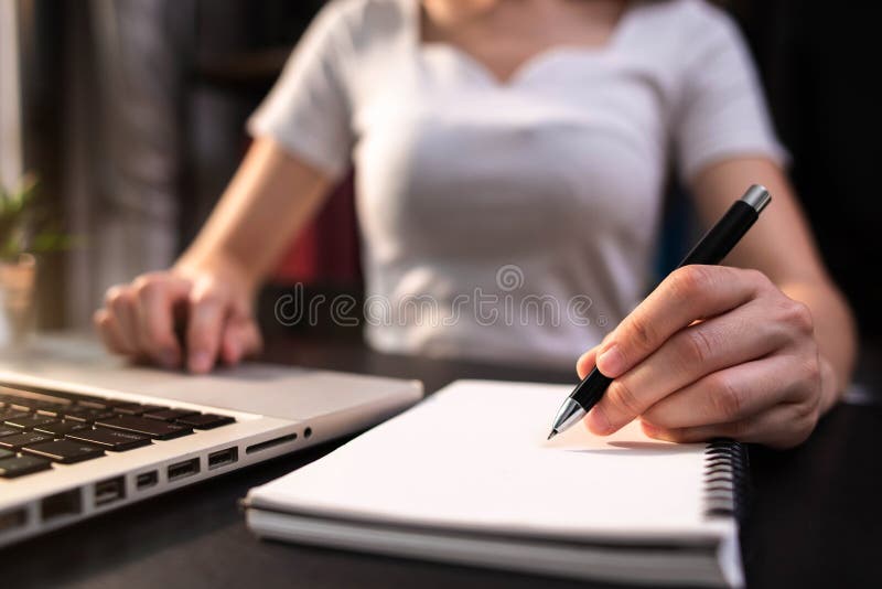 Female Businessman Use a Laptop Computer and Take Notes in the Notebook ...