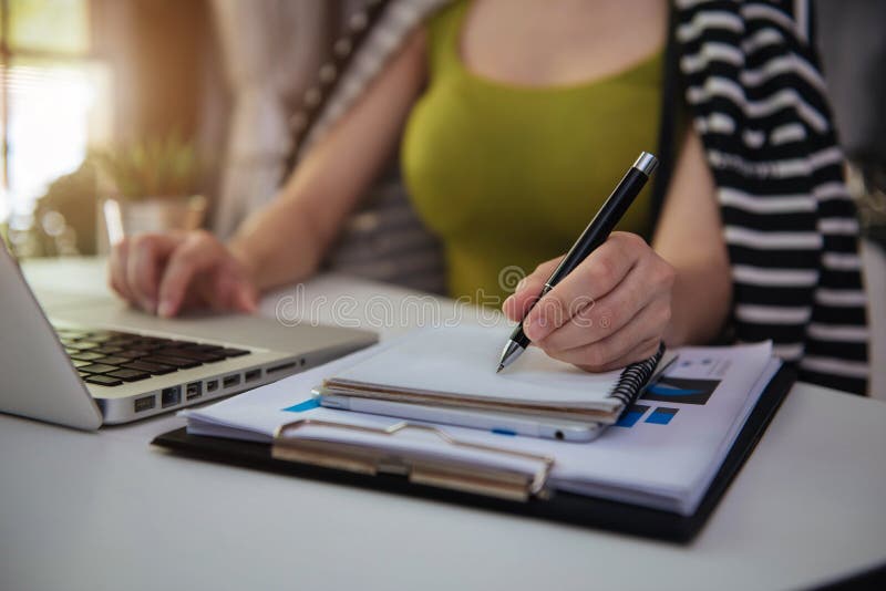 Female Businessman Use a Laptop Computer and Take Notes in the Notebook ...