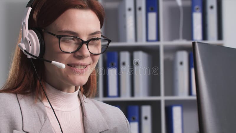Female Call Center Operator in Glasses Communicates with a Client Using ...
