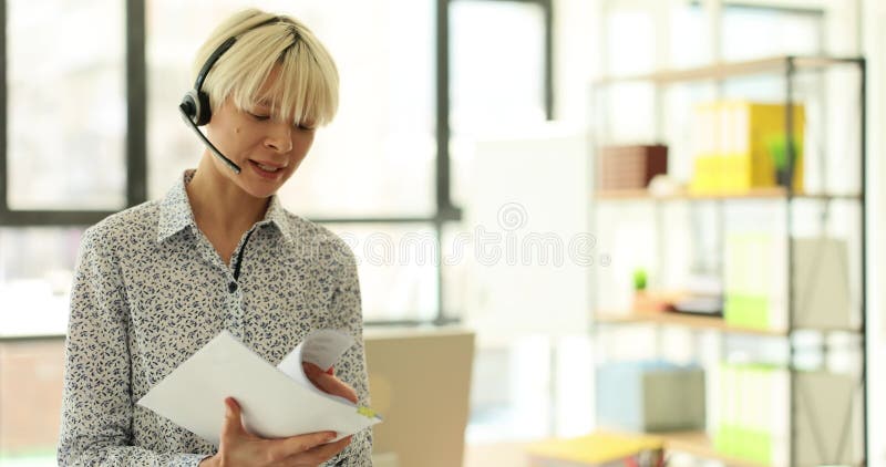 Female Call Center Operator at Work Holds Documents and Communicates ...